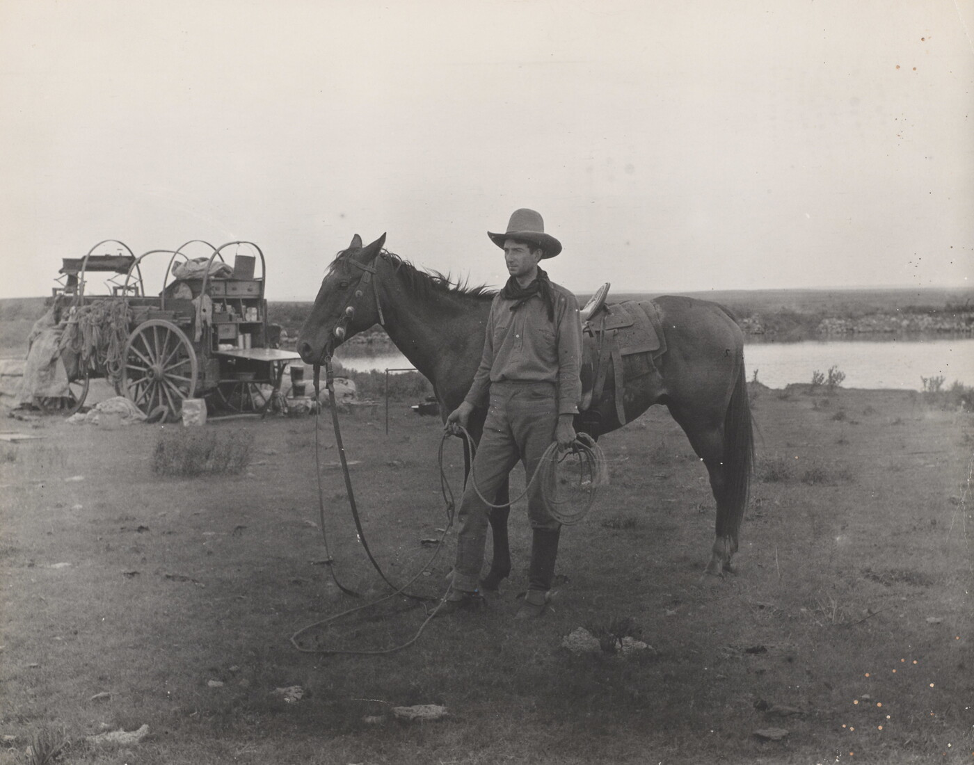 Erwin E. Smith in roundup camp with his mount holding his lariat with ...